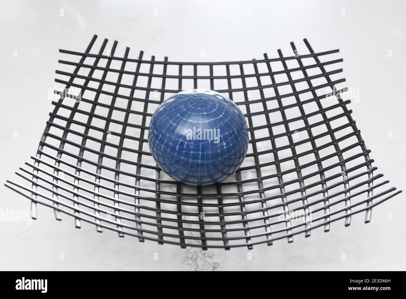 Blue orb sitting on wire mesh looking like earth distorting spacetime ...