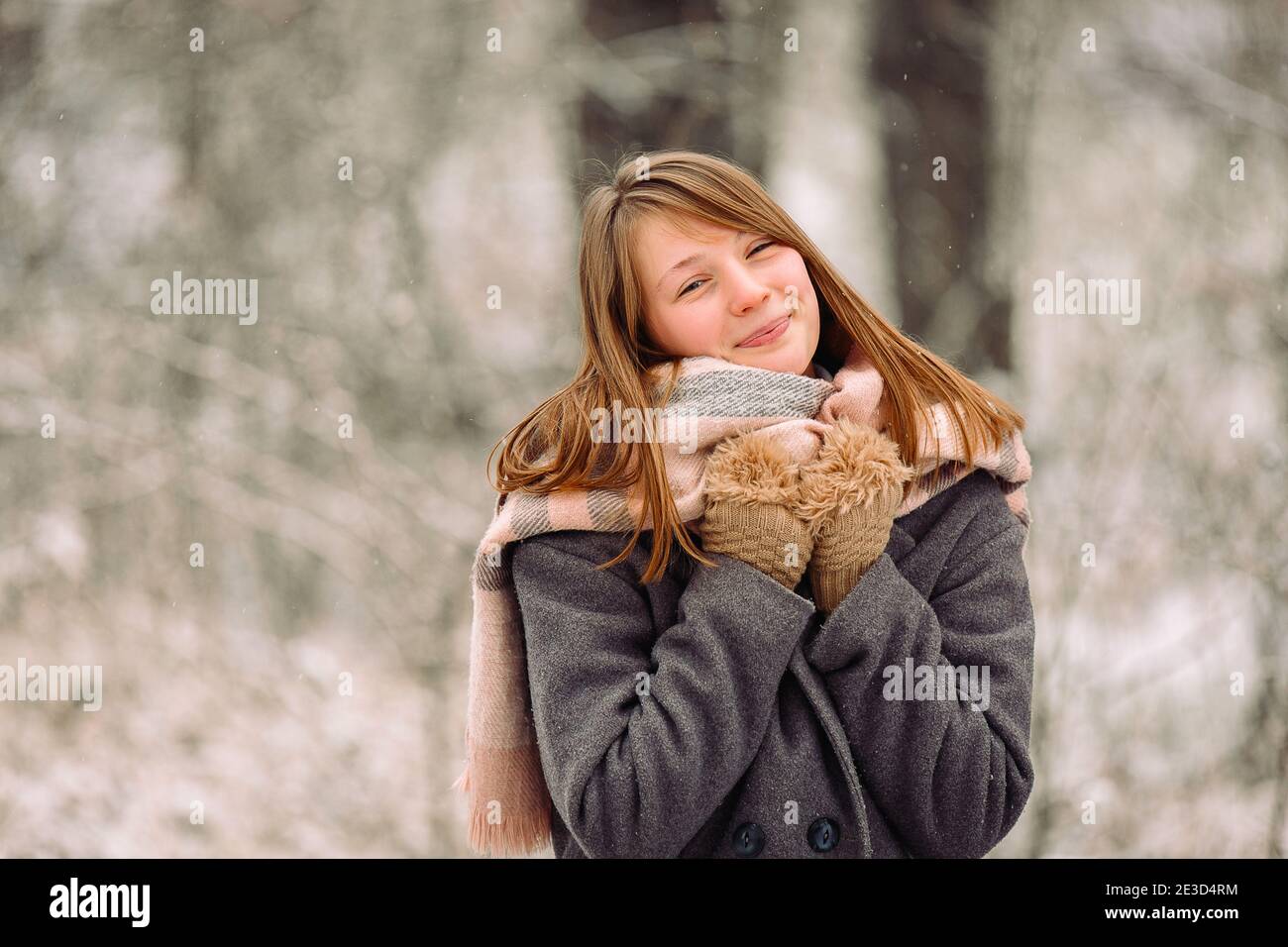 Portrait of a smiling blonde girl in a warm scarf and gloves in the ...