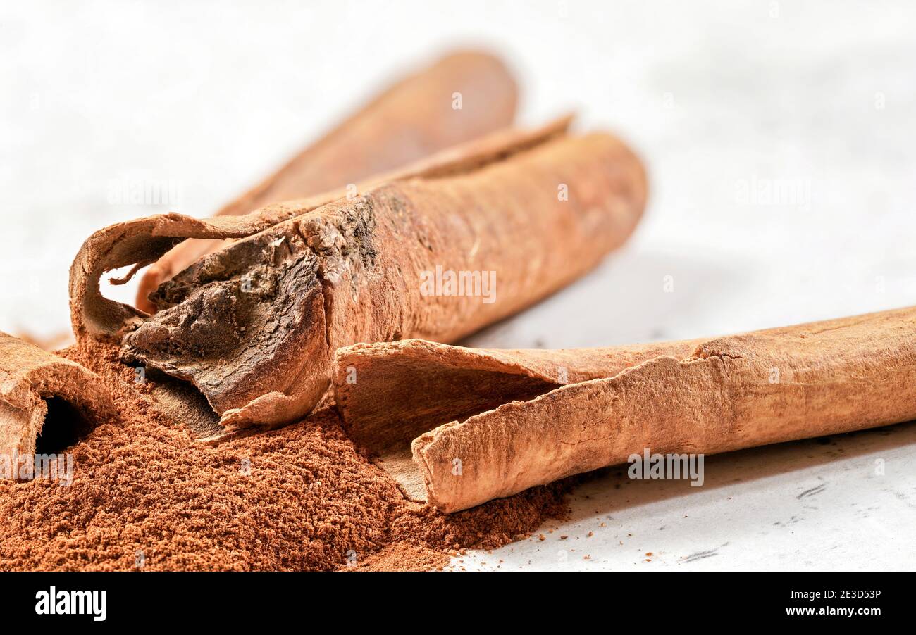 Closeup detail - Heap of cinnamon bark sticks on white stone like desk ...
