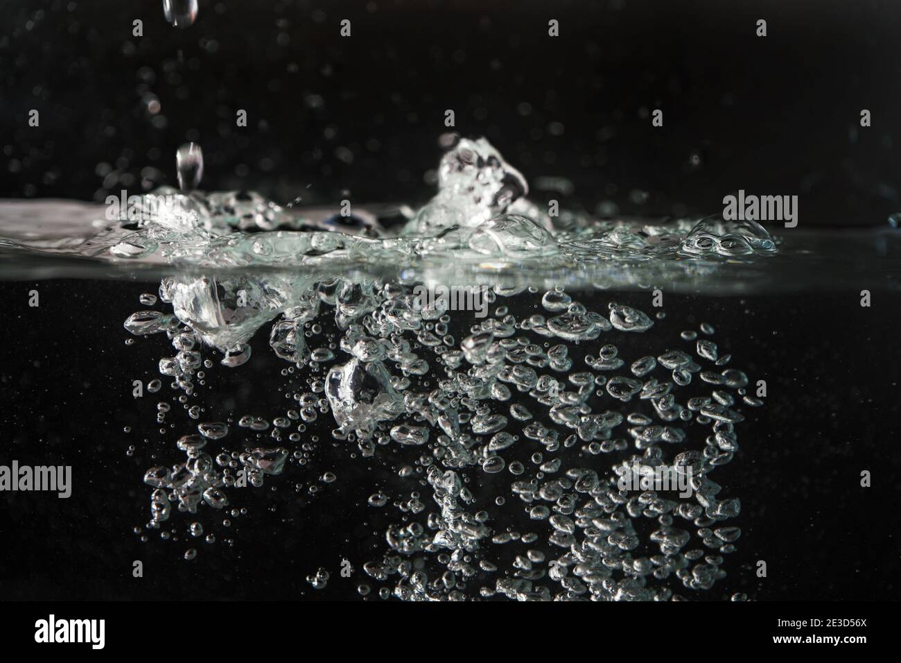 Water splashing as it's poured into aquarium tank, black background ...