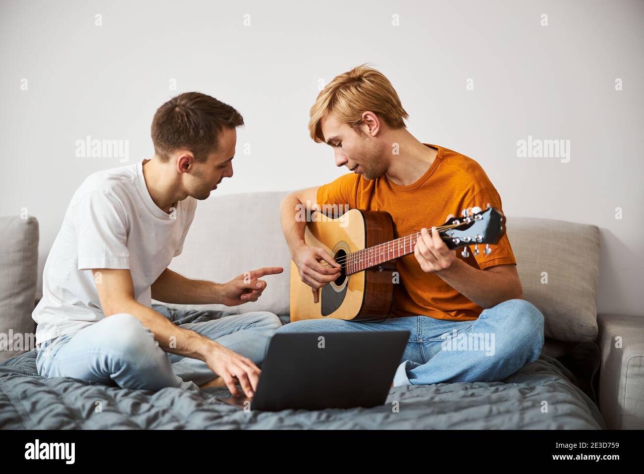 Male musician playing guitar and spending time with boyfriend Stock ...