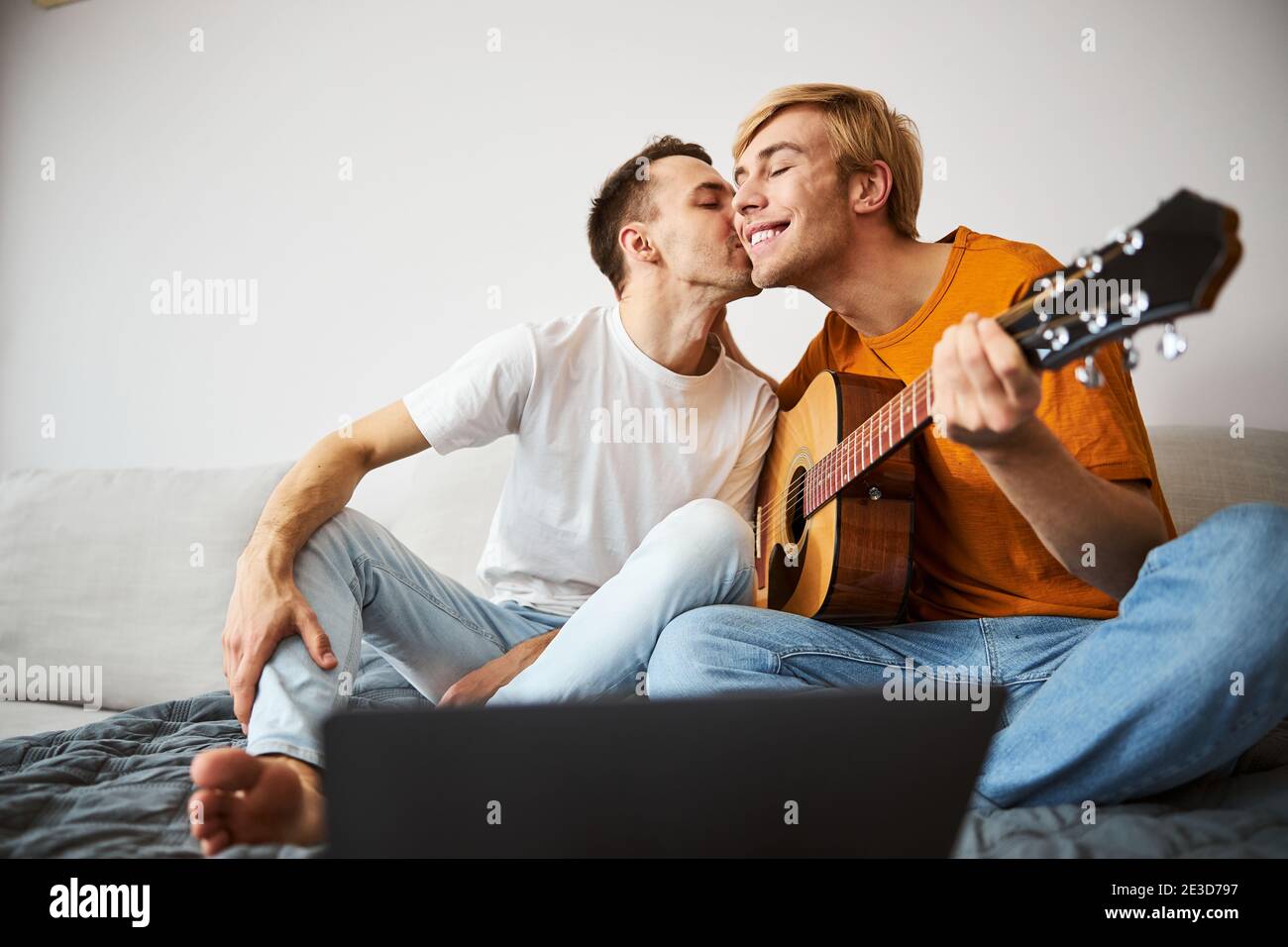 Cheerful male musician sharing tender moment with boyfriend at home ...