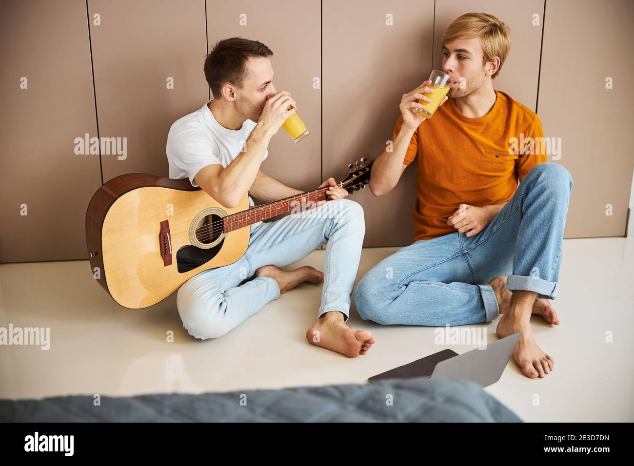 Two handsome young men drinking juice at home Stock Photo - Alamy