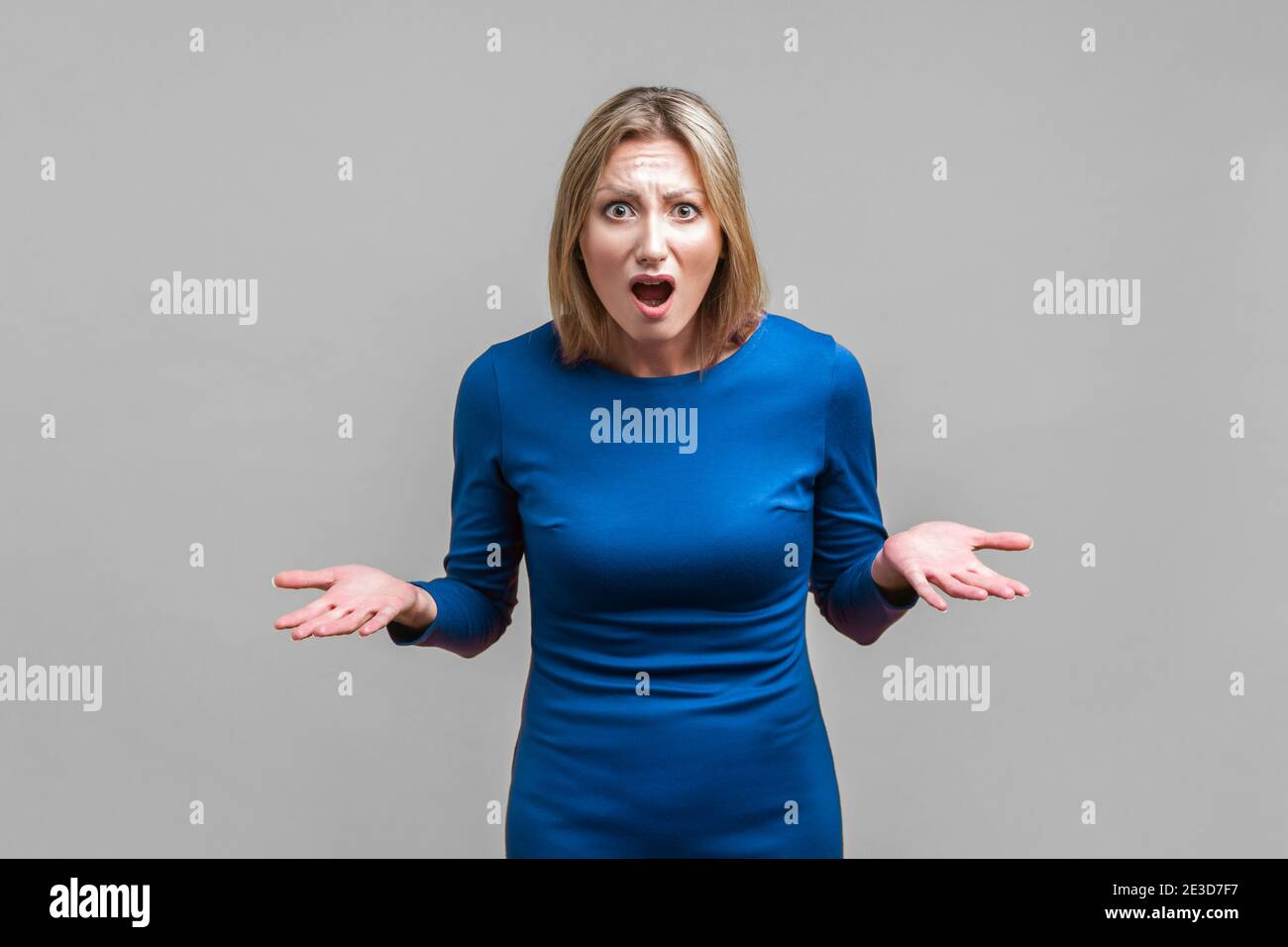 What do you want? Portrait of irritated angry woman in tight blue dress ...