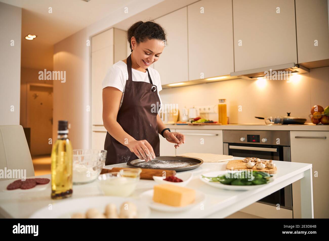 Mirthful young lady cooking pizza and enjoying it Stock Photo - Alamy