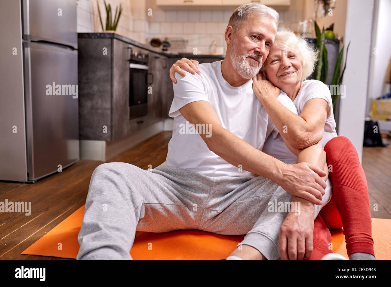 senior couple having rest on the floor after yoga exercises, in ...