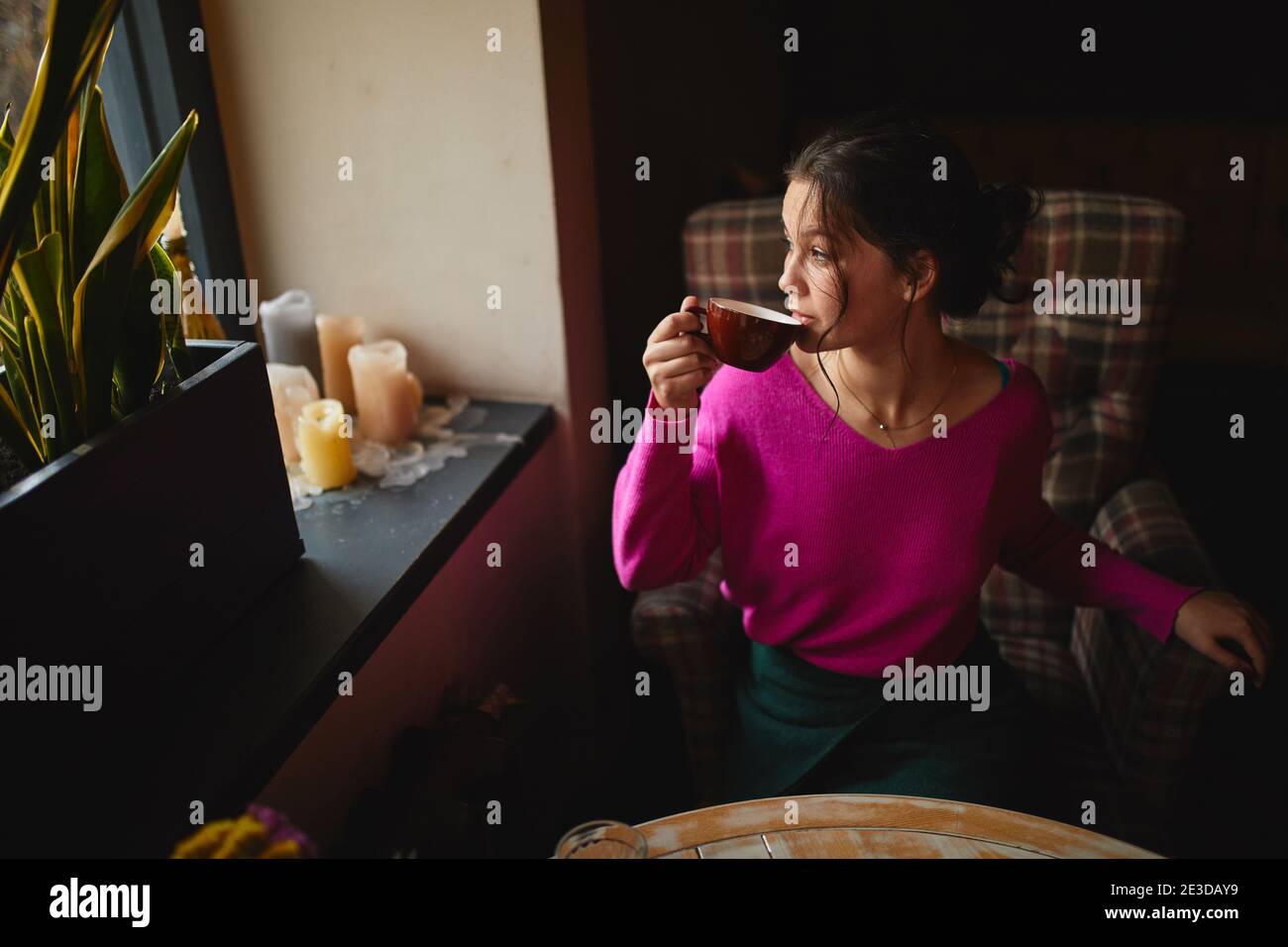 Top view of young female holding red cup and sitting in cafe while ...