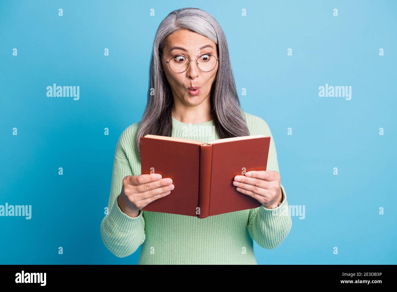 Photo portrait of shocked woman reading red book holding in two hands ...