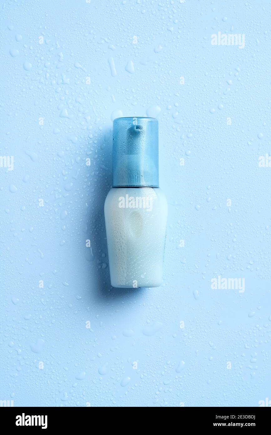 Refreshing shampoo in transparent bottle on blue background. Cosmetics ...