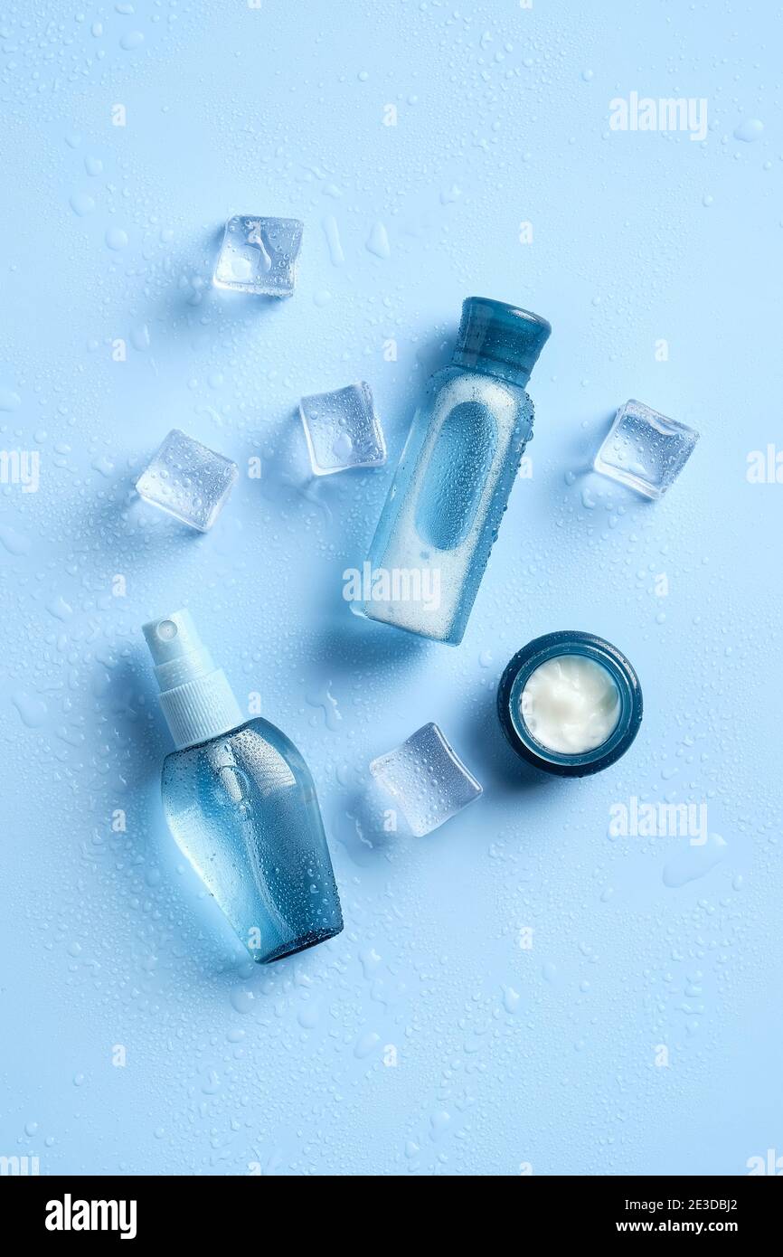Set of hydration cosmetics and ice cubes on blue background. Flat lay ...