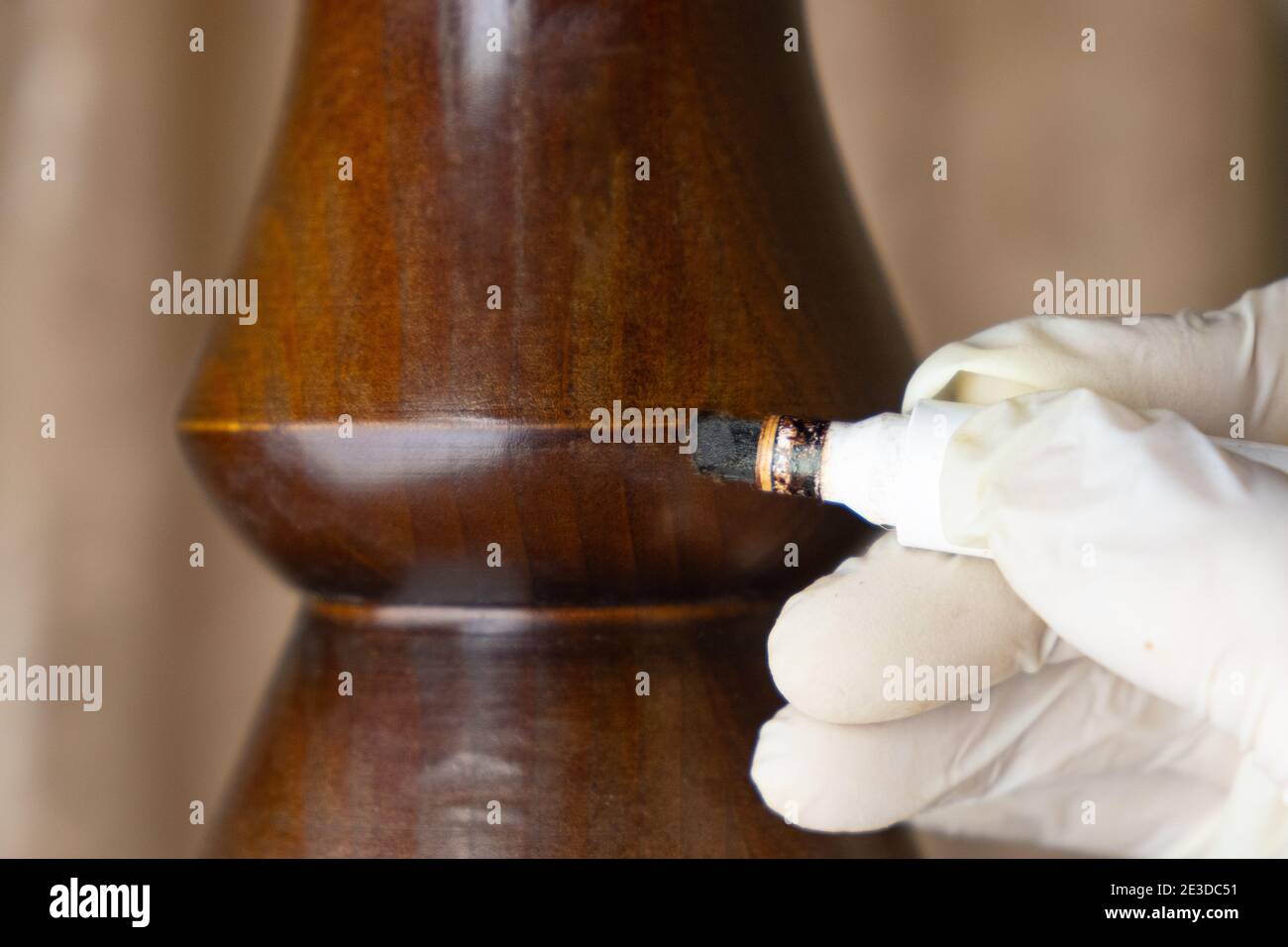 the master removes a scratch on a wooden leg with a special marker ...