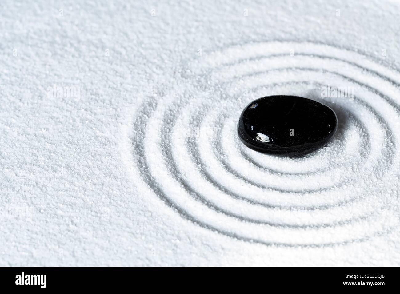 Single black stone on white sand - Zen garden Stock Photo - Alamy