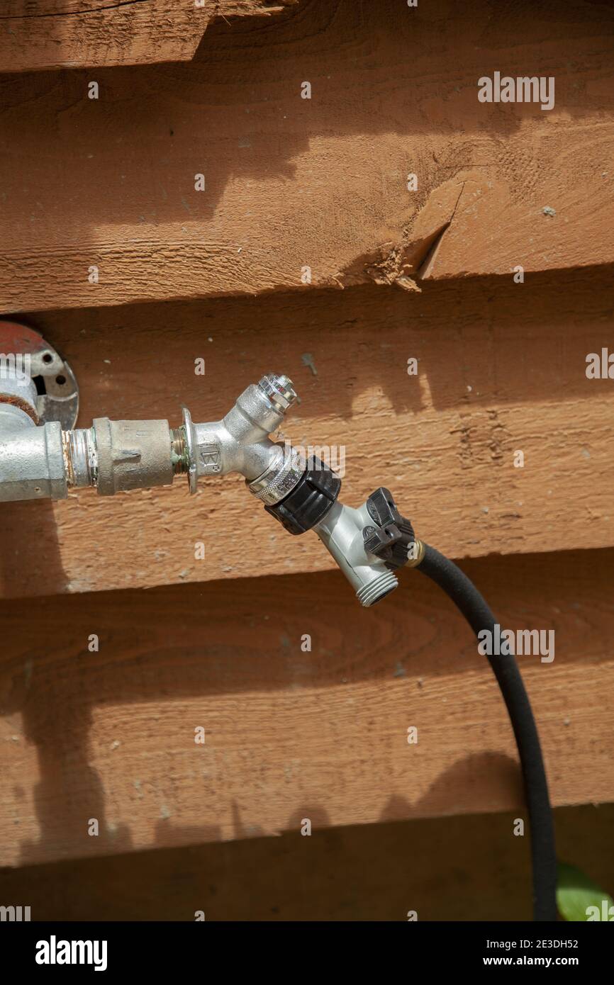 Metal outdoor water spigot near a brown planked building Stock Photo ...