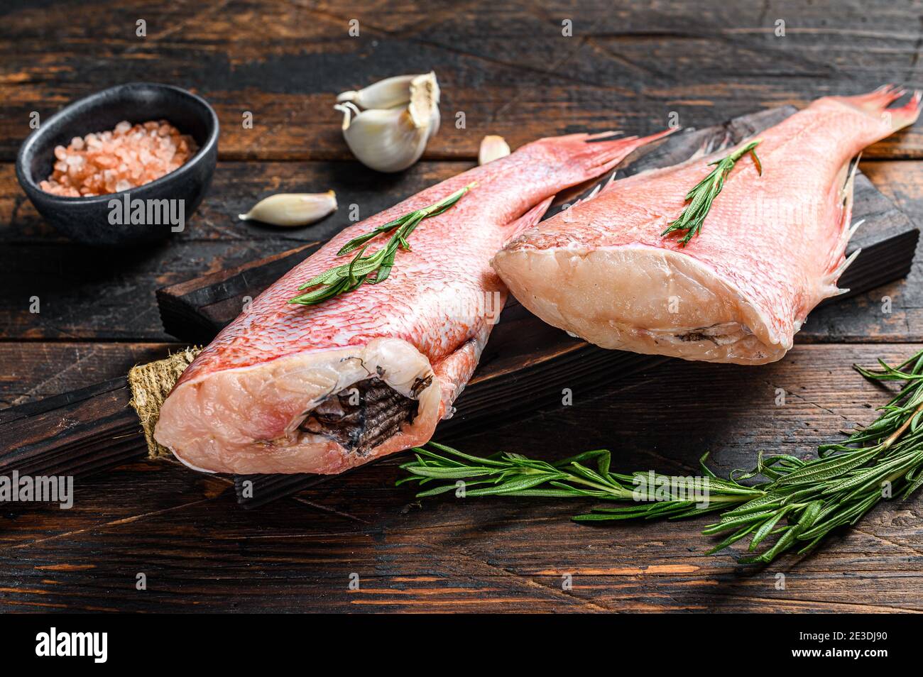 Whole raw fresh red perch or seabass fish. Dark wooden background. Top ...