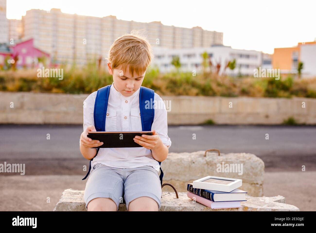 Little school boy studying outdoors school yard on warm sunny day ...