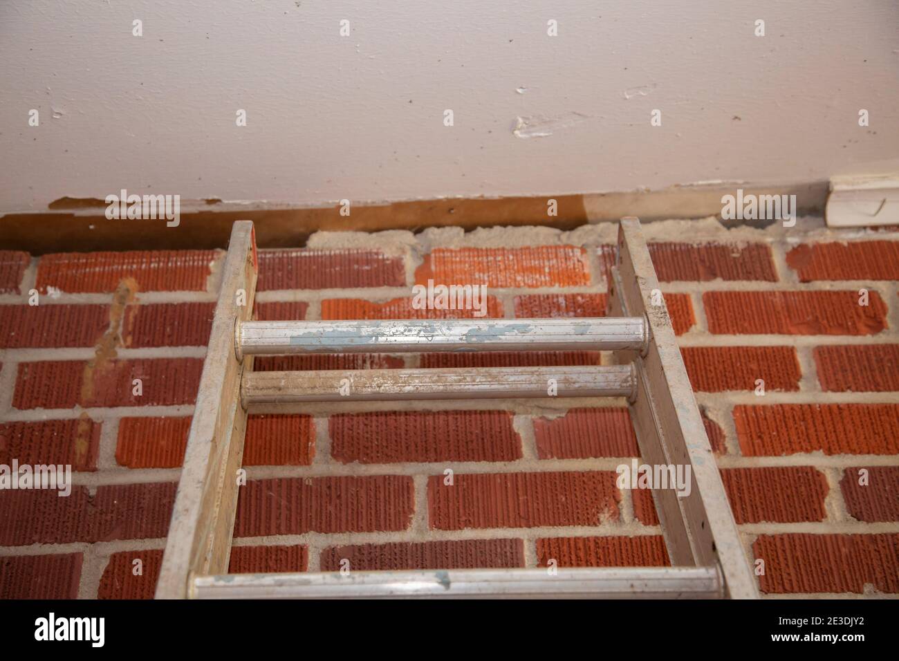 Top of a ladder against a red brick wall, leading to a ceiling Stock ...
