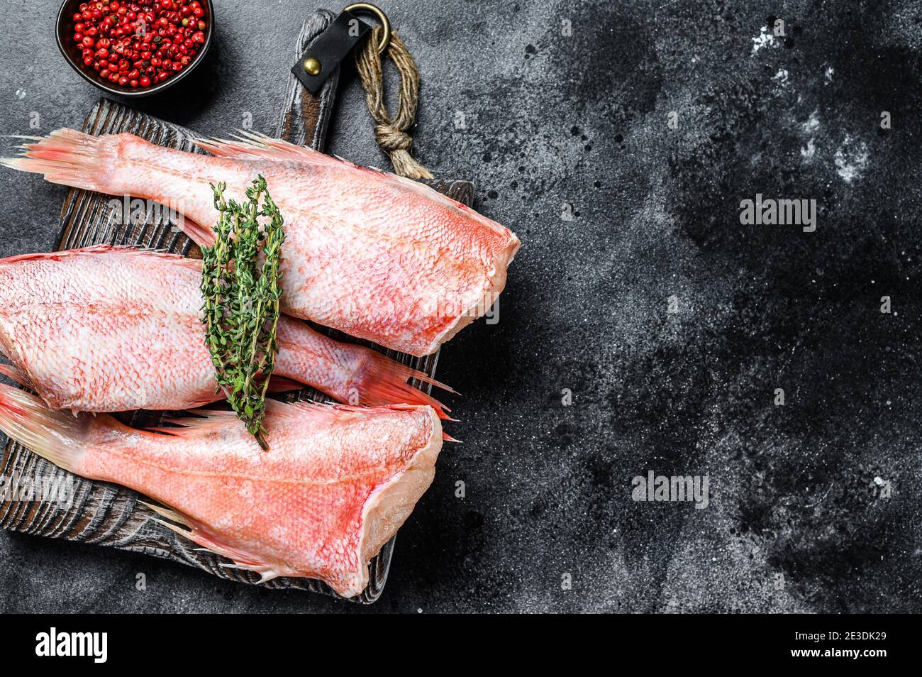 Whole raw red snapper fish on a cutting board. Black background. Top ...