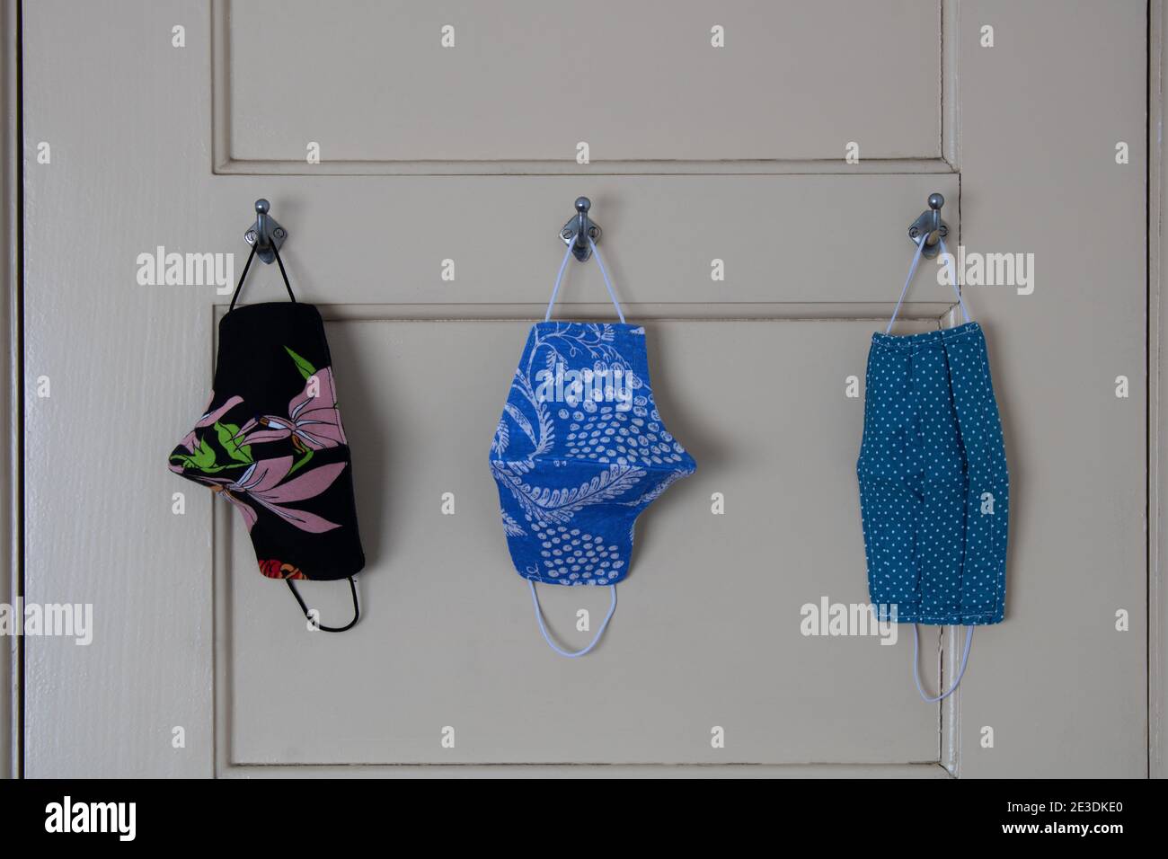 Three covid-19 cloth face masks hanging on door hooks at home ready to ...