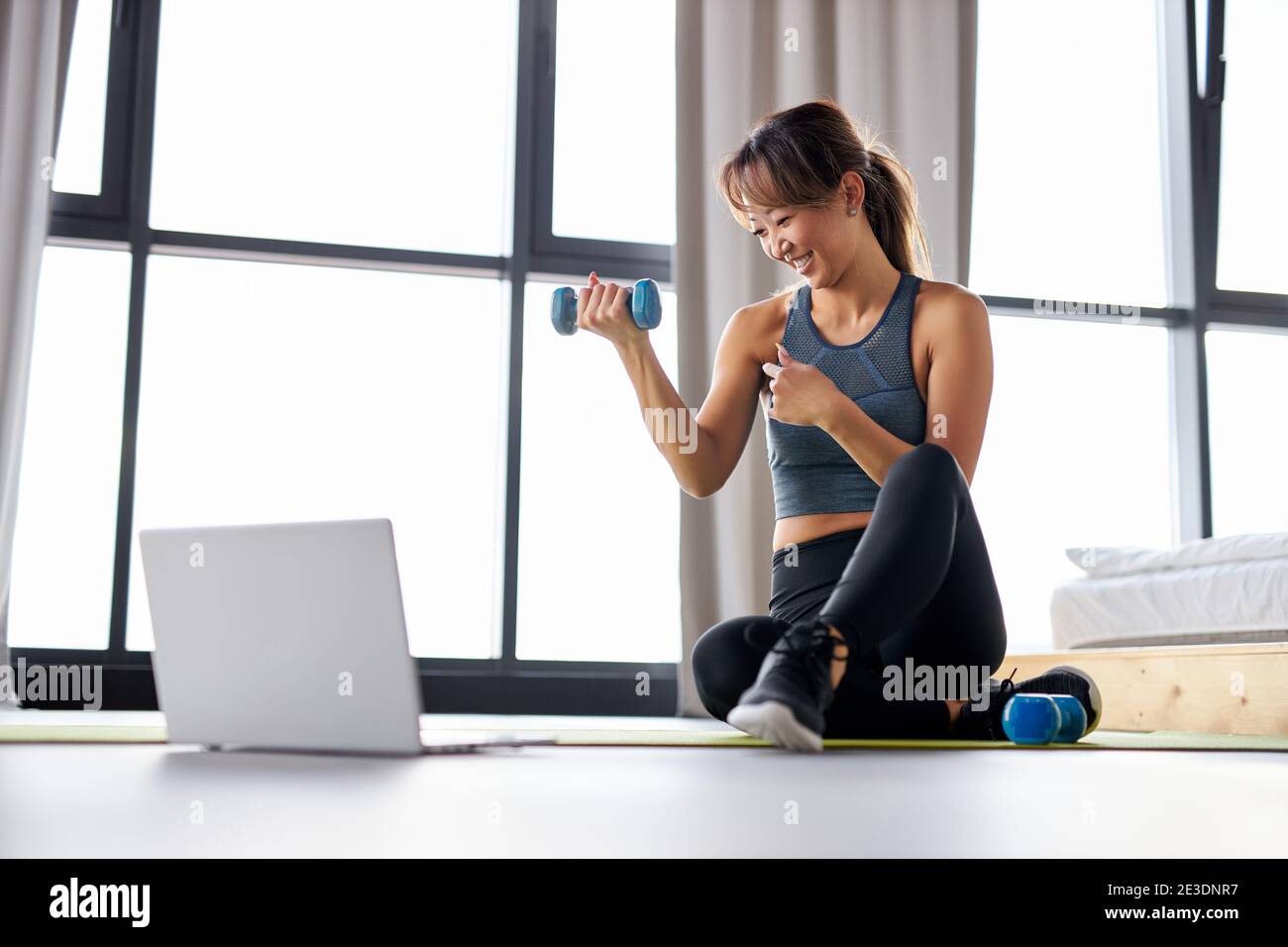 asian woman excercising at home, watching video tutorial on laptop ...
