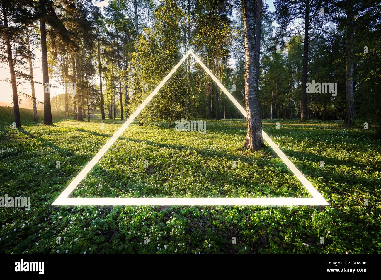 Futuristic, bright, glowing neon lighting triangle at lush greenspace ...