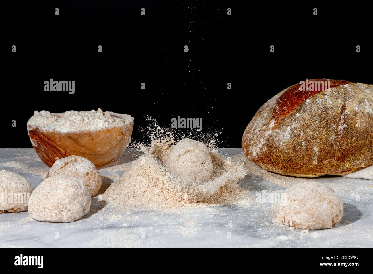 A bread loaf splash on a pile of wholewheat flour on marble countertop ...