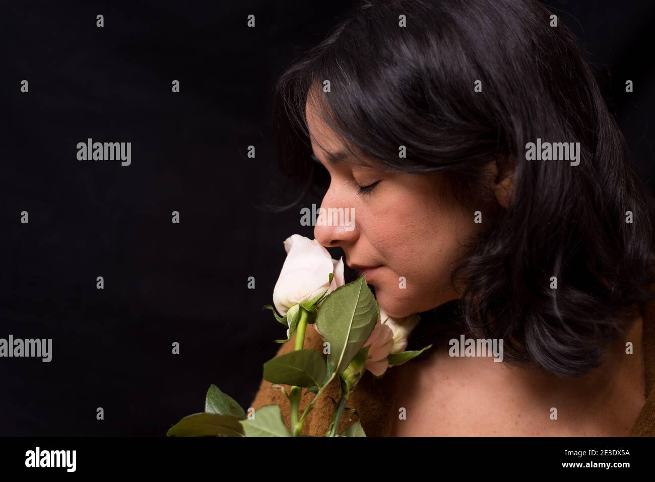 close up of beautiful young woman smelling white rose on black ...