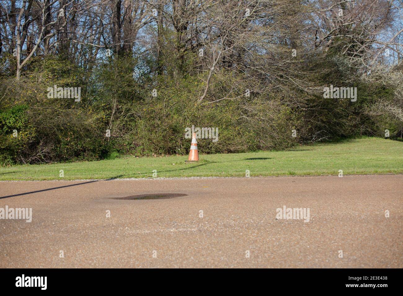 Orange caution cone with two white stripes in a yard near bushes Stock ...
