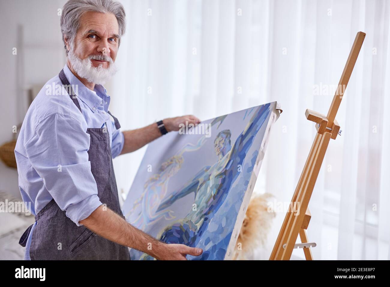 senior artist remove the canvas from the easel, prepared painting in ...