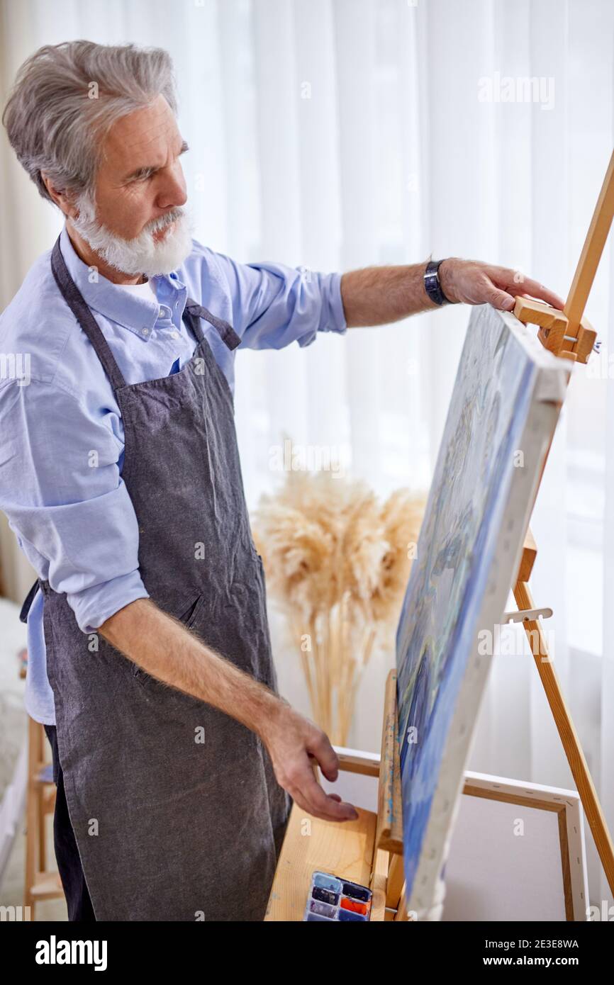 senior artist painting on easel, canvas, intelligent professional ...