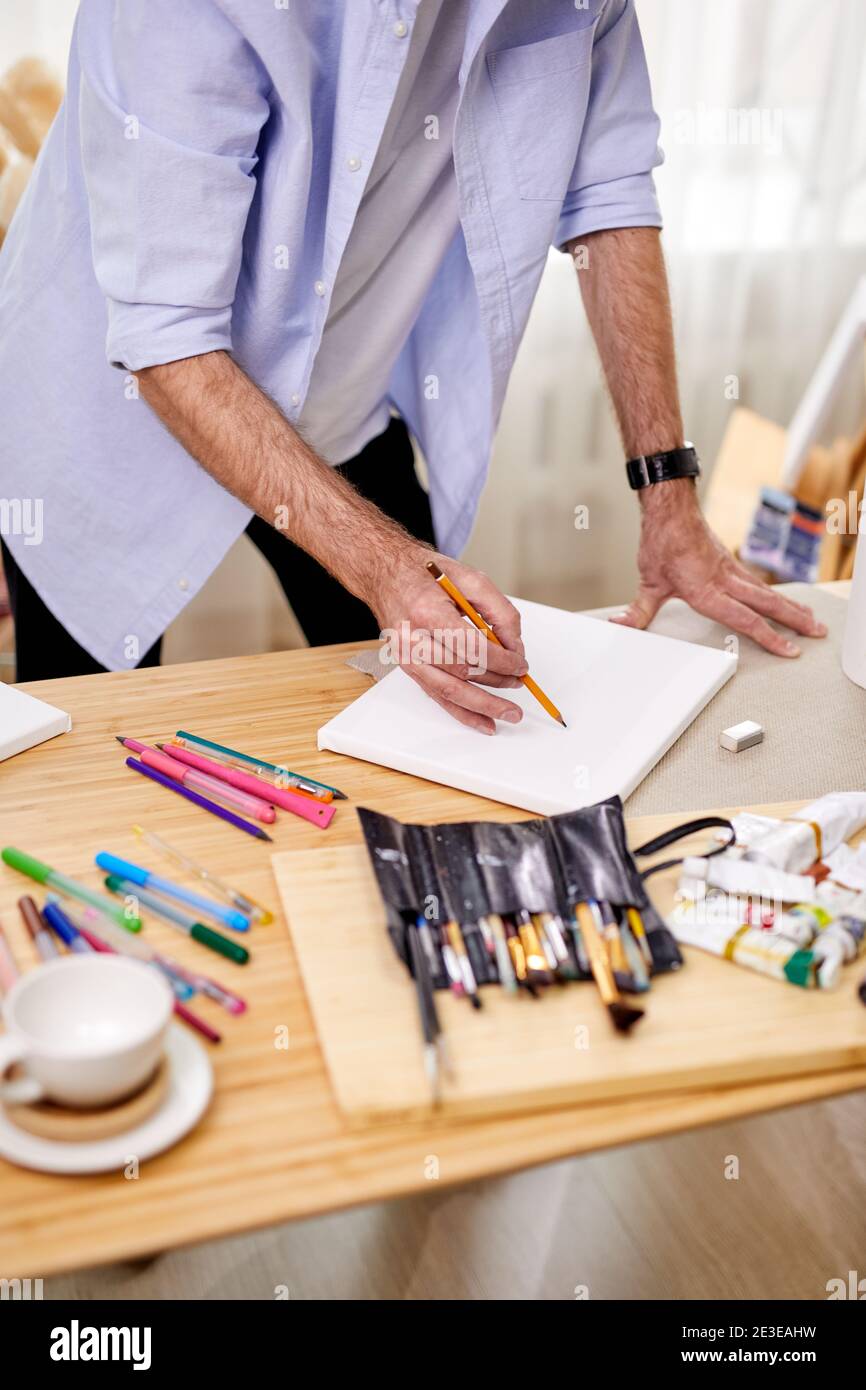 skilled painter drawing sketch on sheet with pencil, tool and materials ...