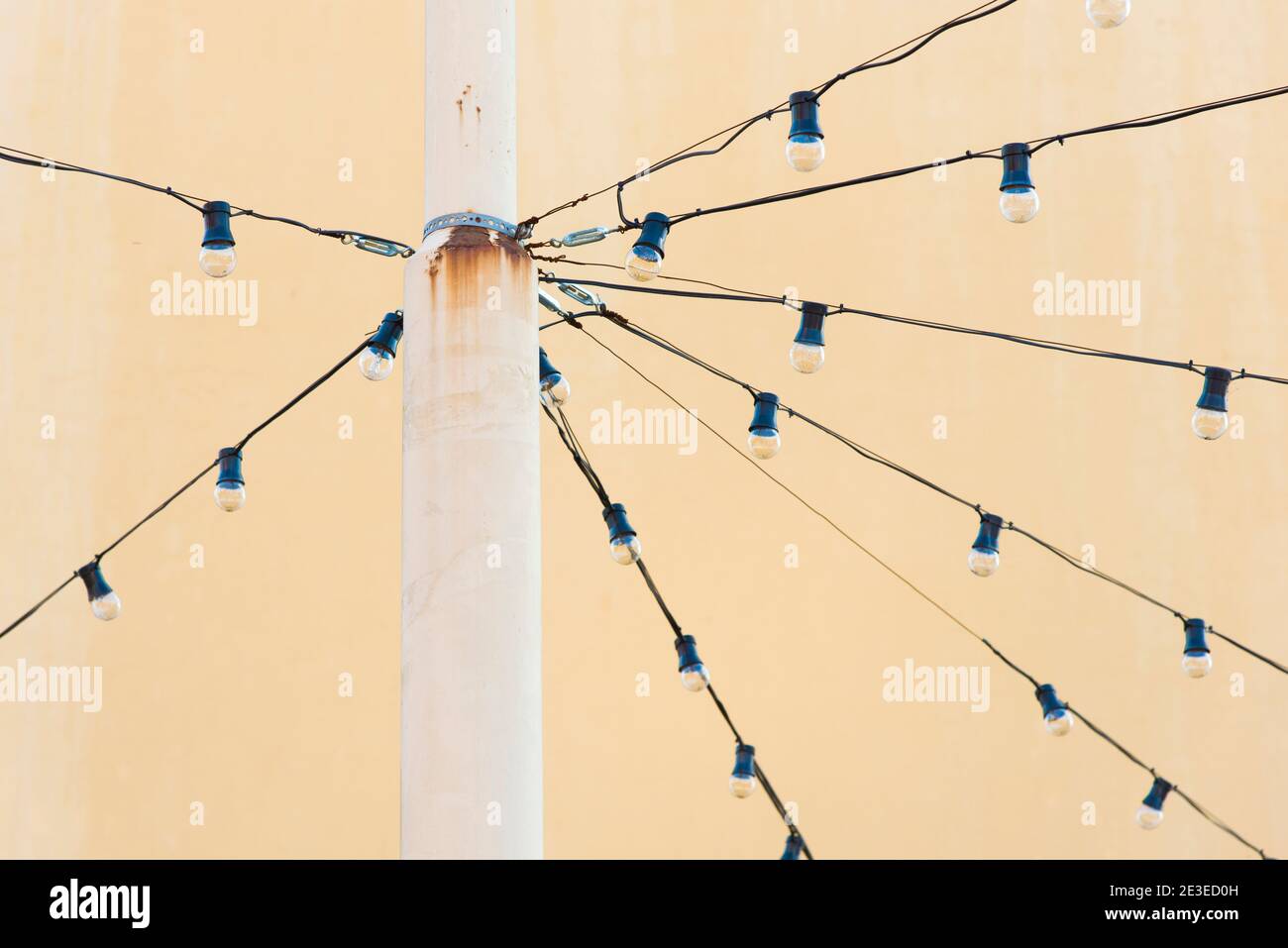 Urban detail, cables with light bulbs tied to a pole radially, on a ...