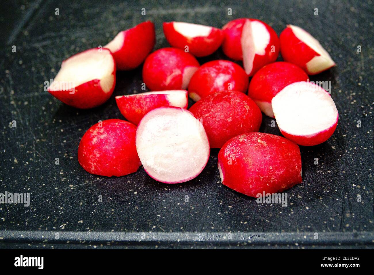 Isolated radishes chopped in halves upon black chopping board Stock ...