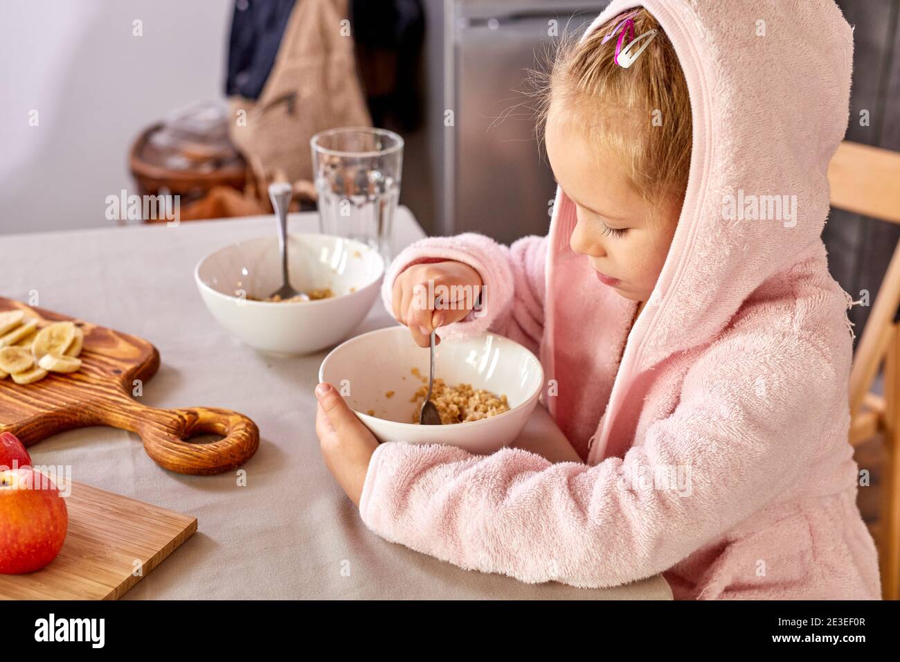 child girl eating breakfast alone in the kitchen, sit having meal by ...