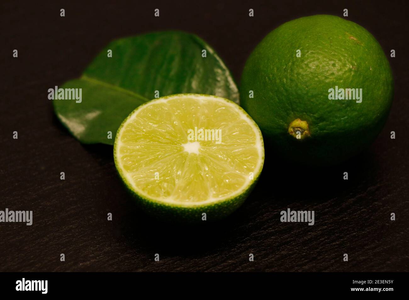 half and whole lime isolated on a black background Stock Photo - Alamy