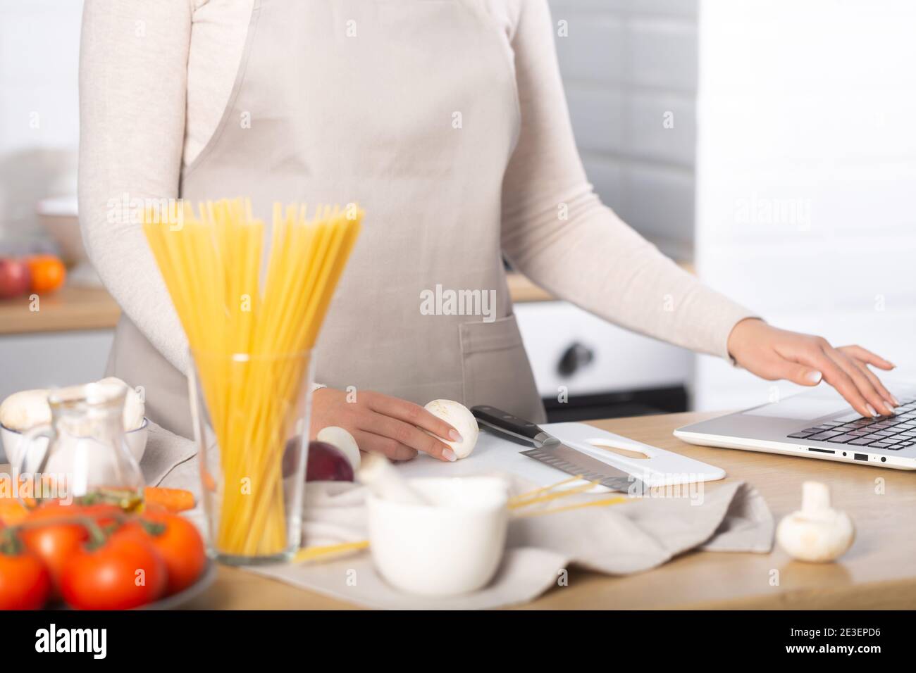 Woman cooking pasta using the computer to watch virtual culinary class ...