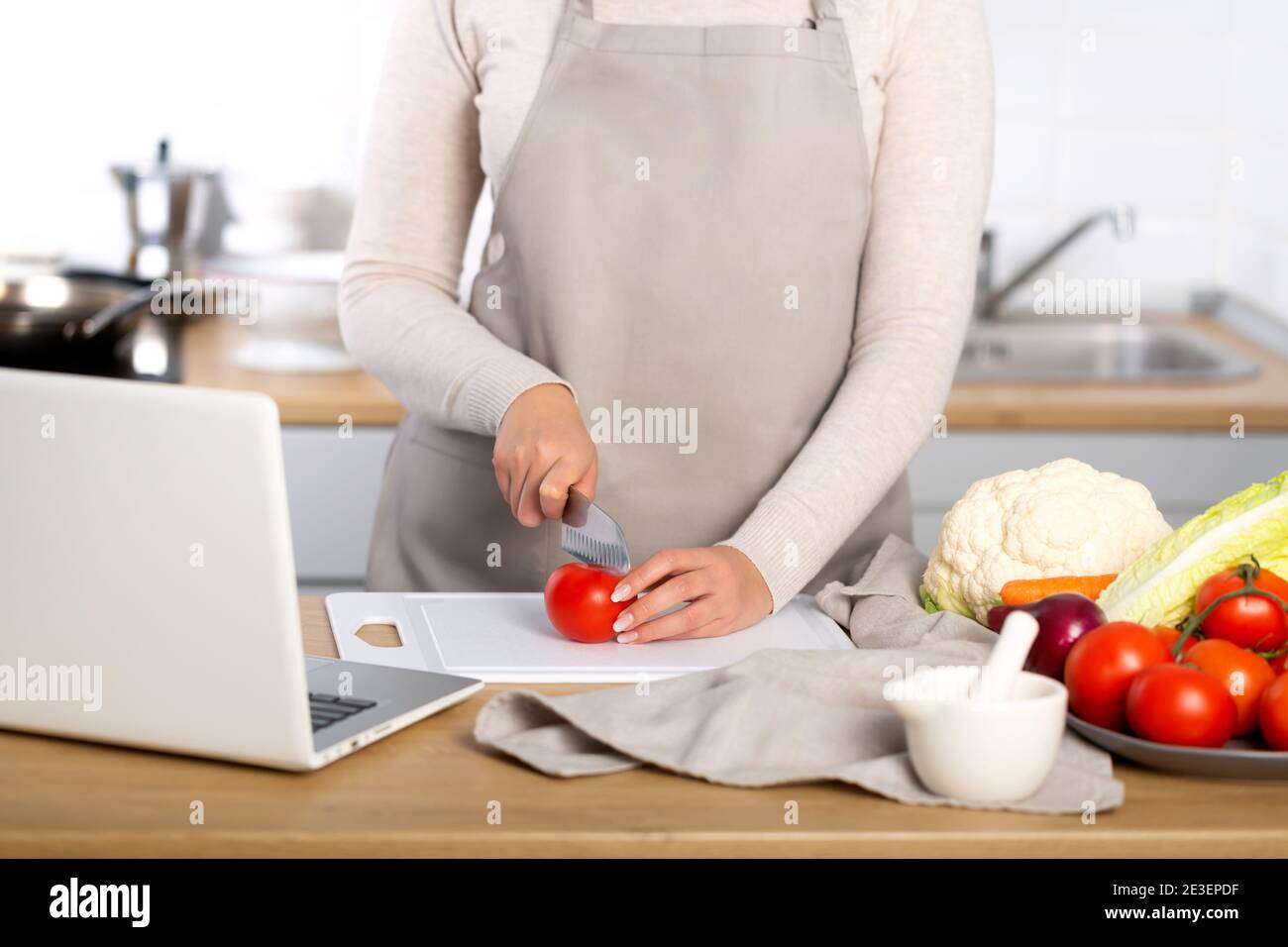 Woman cooking using the computer to watch virtual culinary class Stock ...