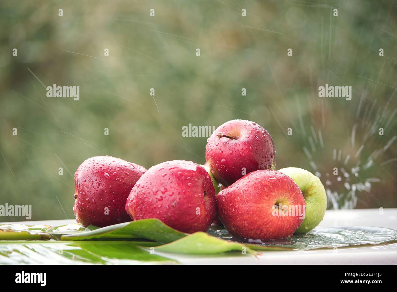 Selective focus shot of fresh apples captured under the pouring rain ...