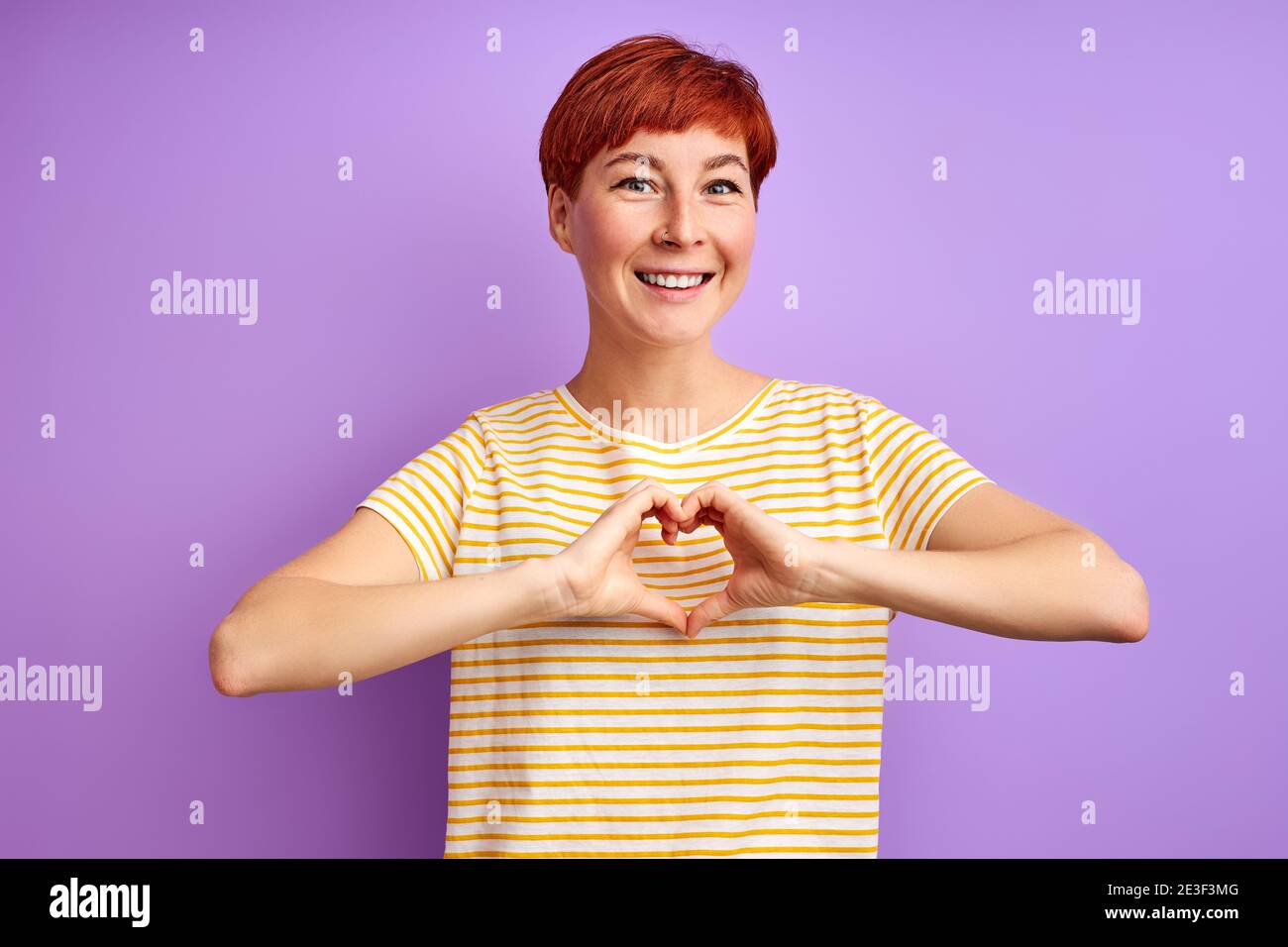woman expresses love at camera showing shape of heart made from hands ...