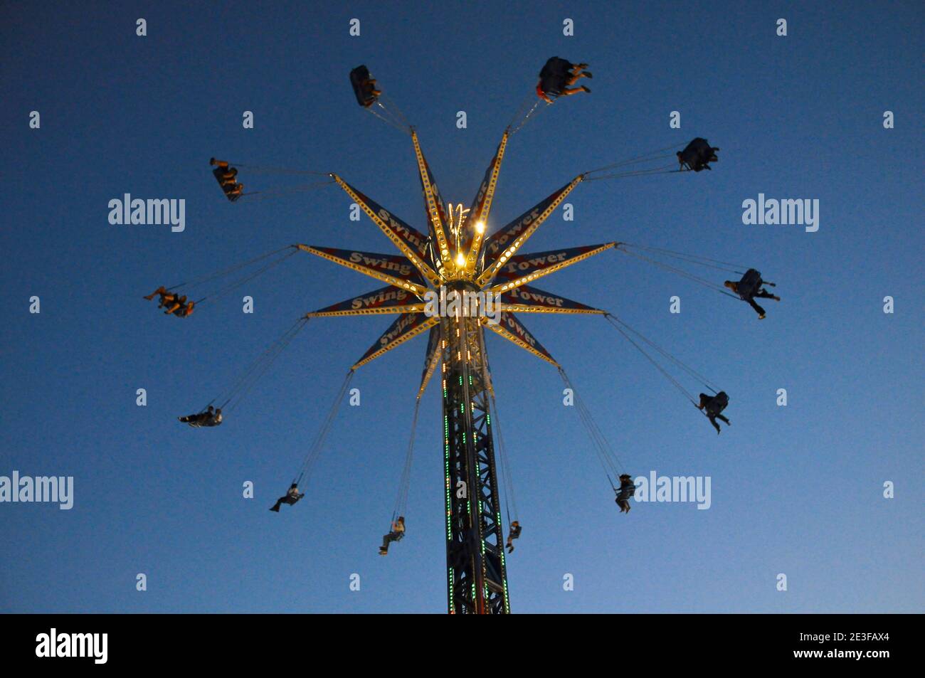 Silhouette image of people swinging high in the sky on an amusement ...
