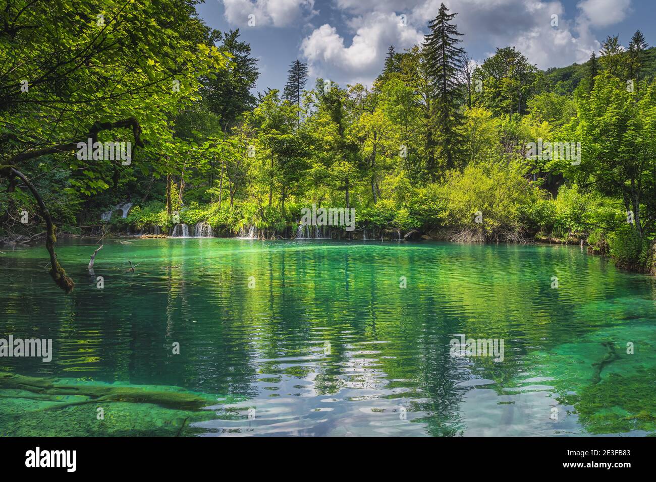 Clean, transparent turquoise pond and green mossy hill with waterfalls ...