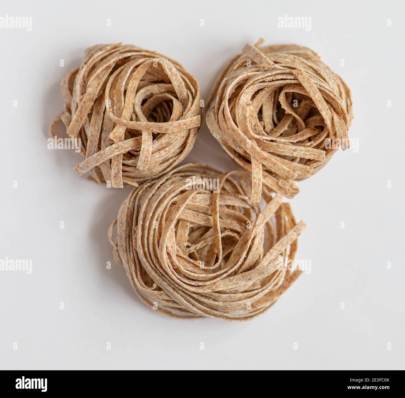 Raw whole grain brown pasta on a white background. Delicate wholemeal ...