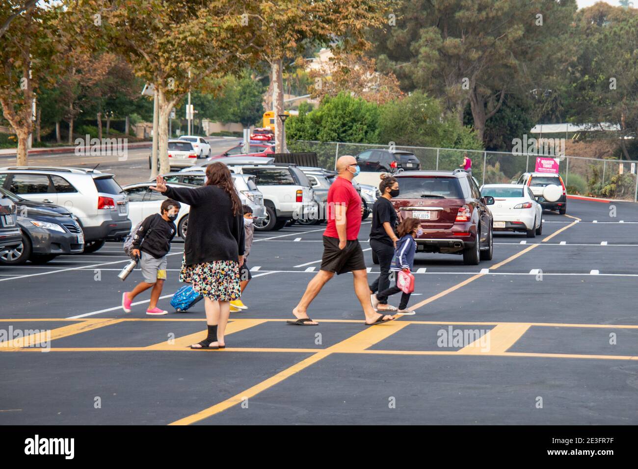 A teacher directs traffic as parents and students arrive for the first ...