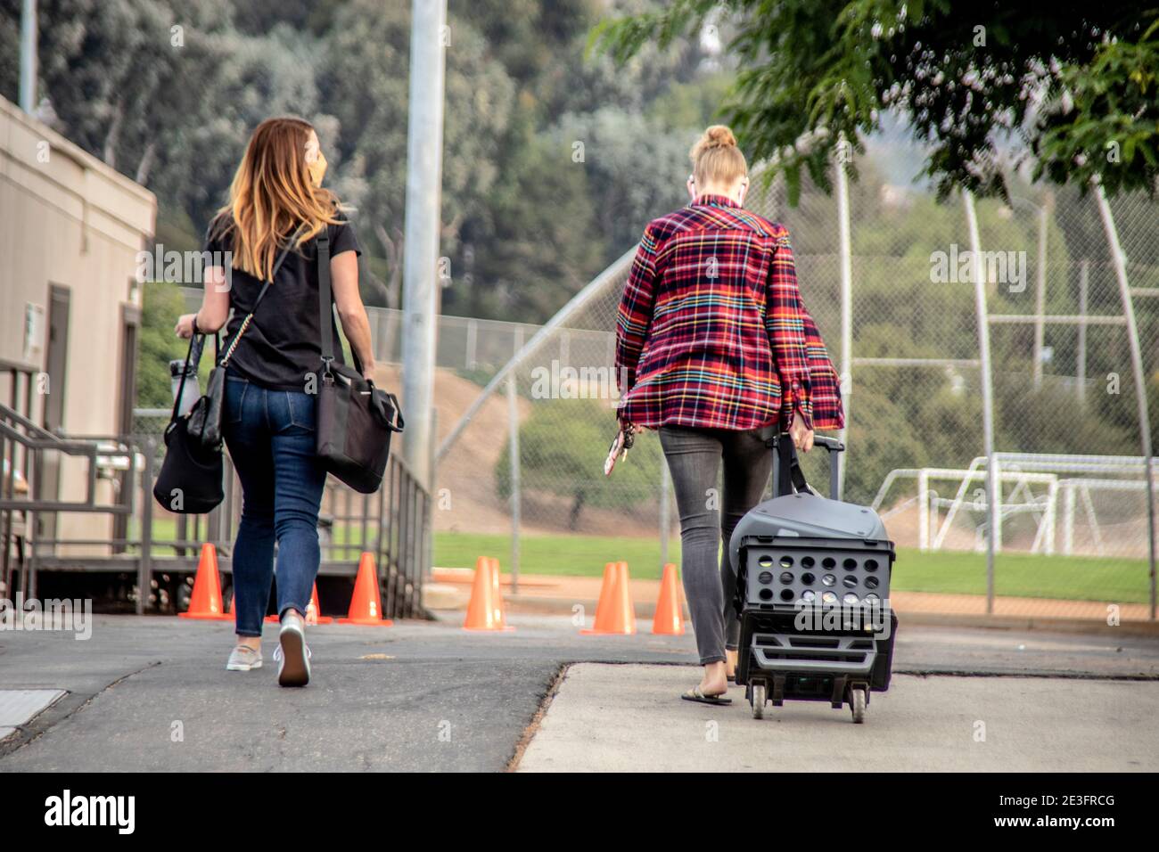 Carrying their educational materials in a shoulder bag and a baggage ...