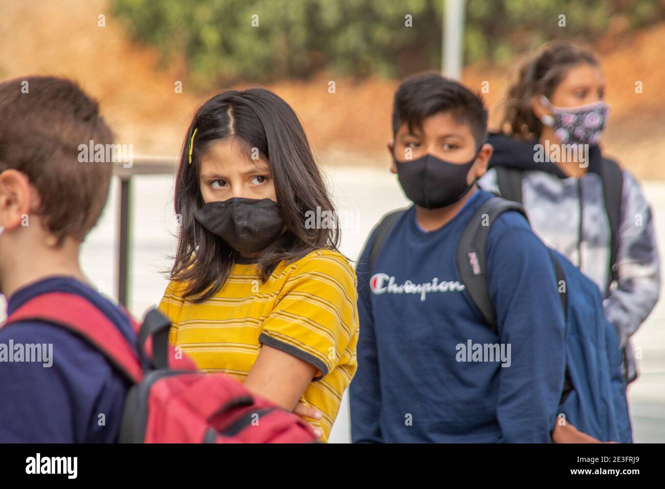 Carrying or wheeling their backpacks, four teen boys arrive at the ...