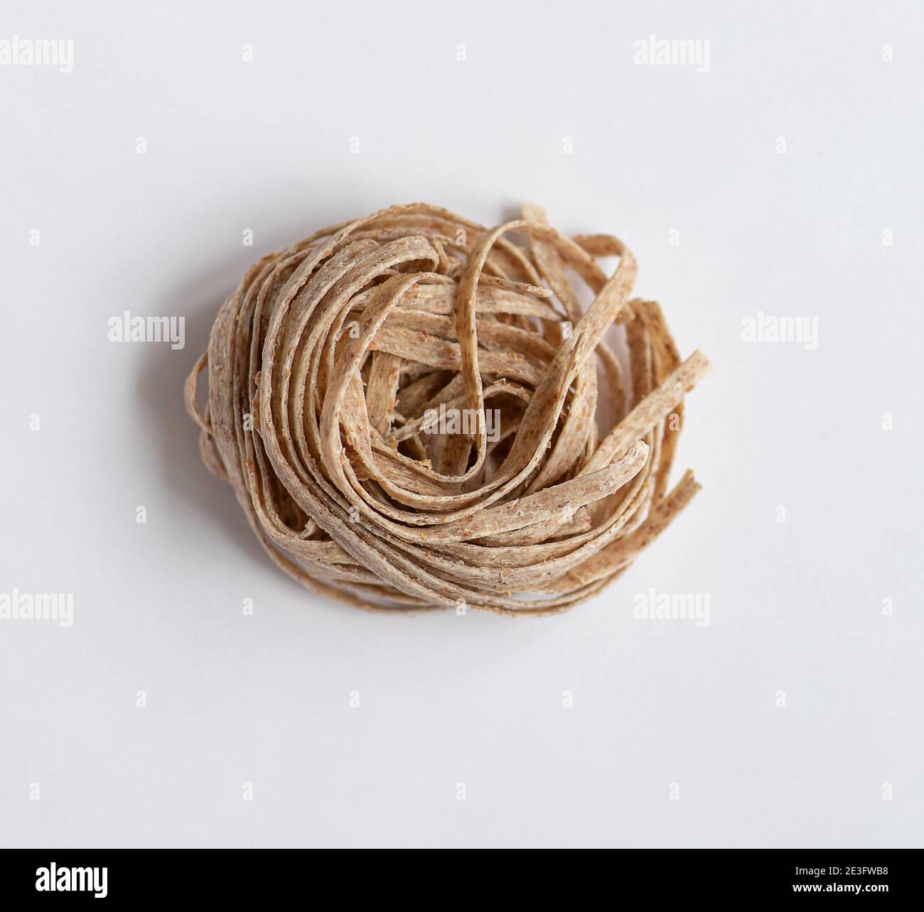 One portion raw whole grain brown pasta on a white background. Delicate ...