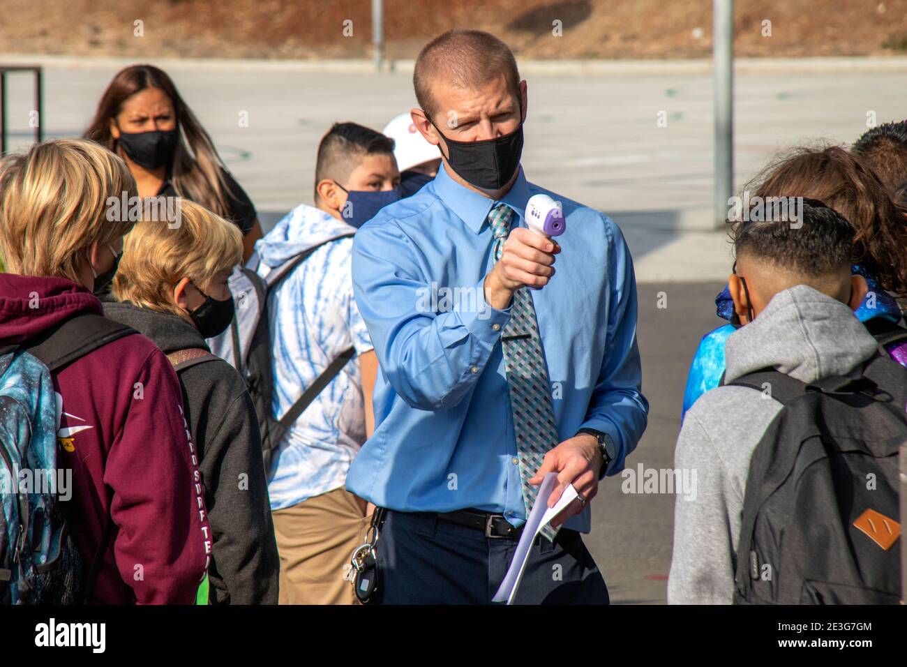 Wearing a safety face mask and using a digital thermometer, a ...