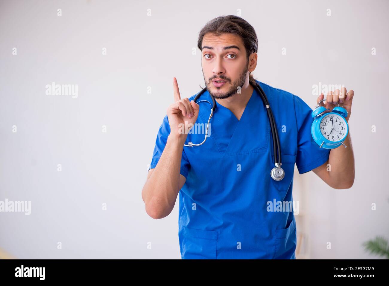 Young doctor in time management concept Stock Photo - Alamy