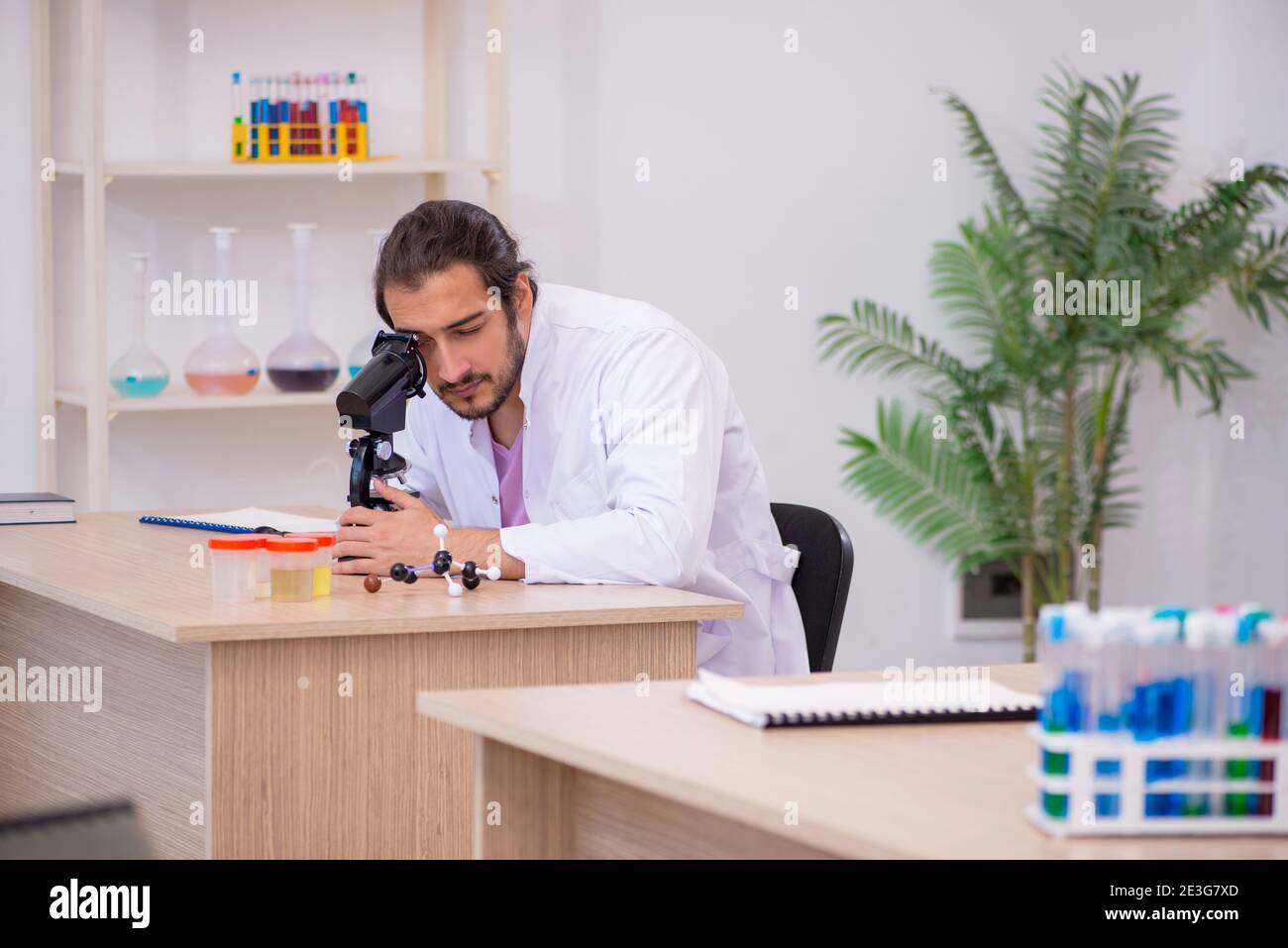 Young chemist sitting at the desk in the classroom Stock Photo - Alamy