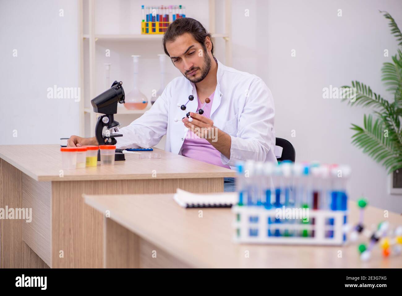 Young chemist sitting at the desk in the classroom Stock Photo - Alamy