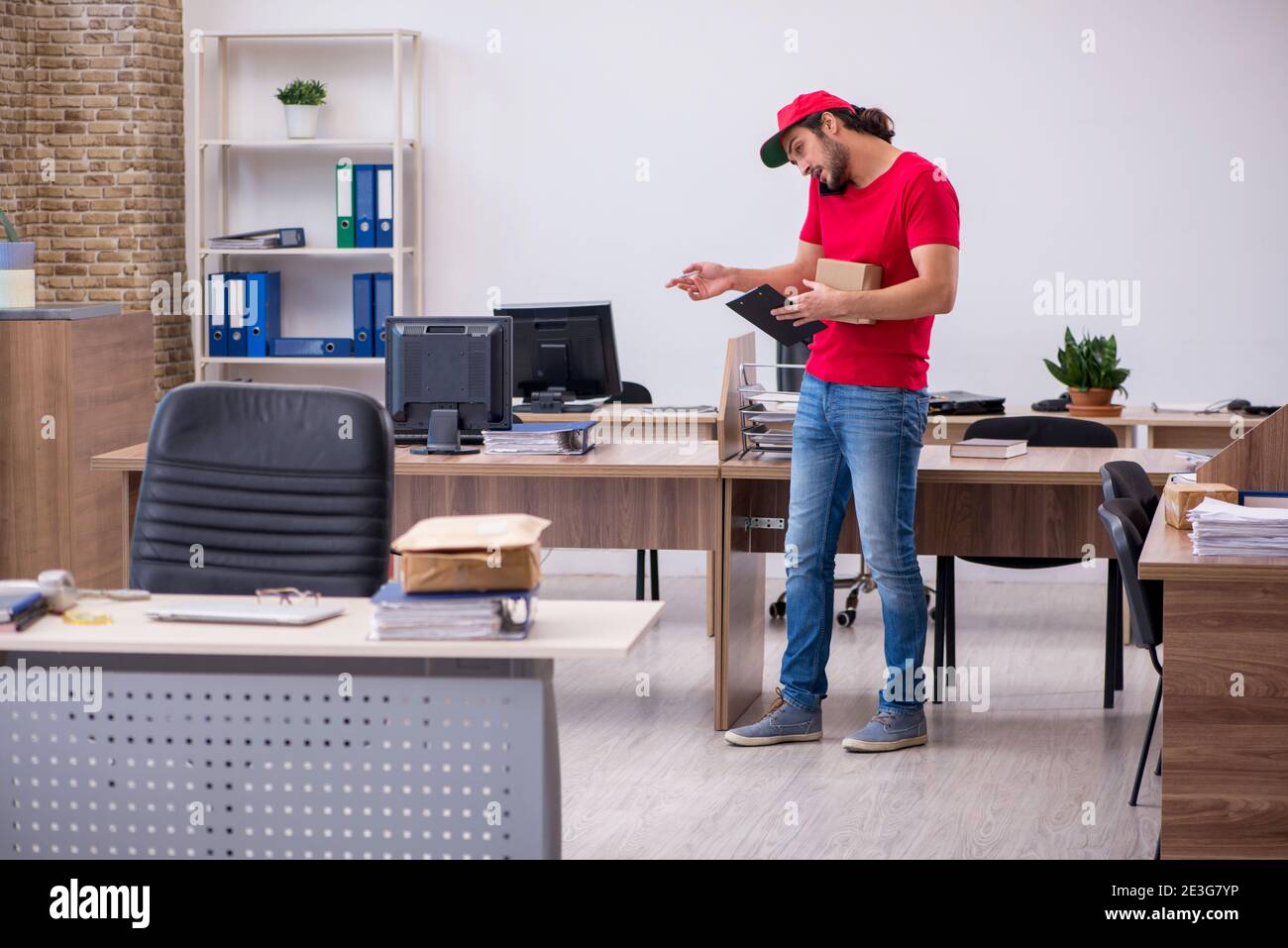 Young courier delivering post to the office Stock Photo - Alamy